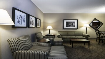 Quarto de hotel com mobiliário riscado, quadros nas paredes e piso coberto por carpete.