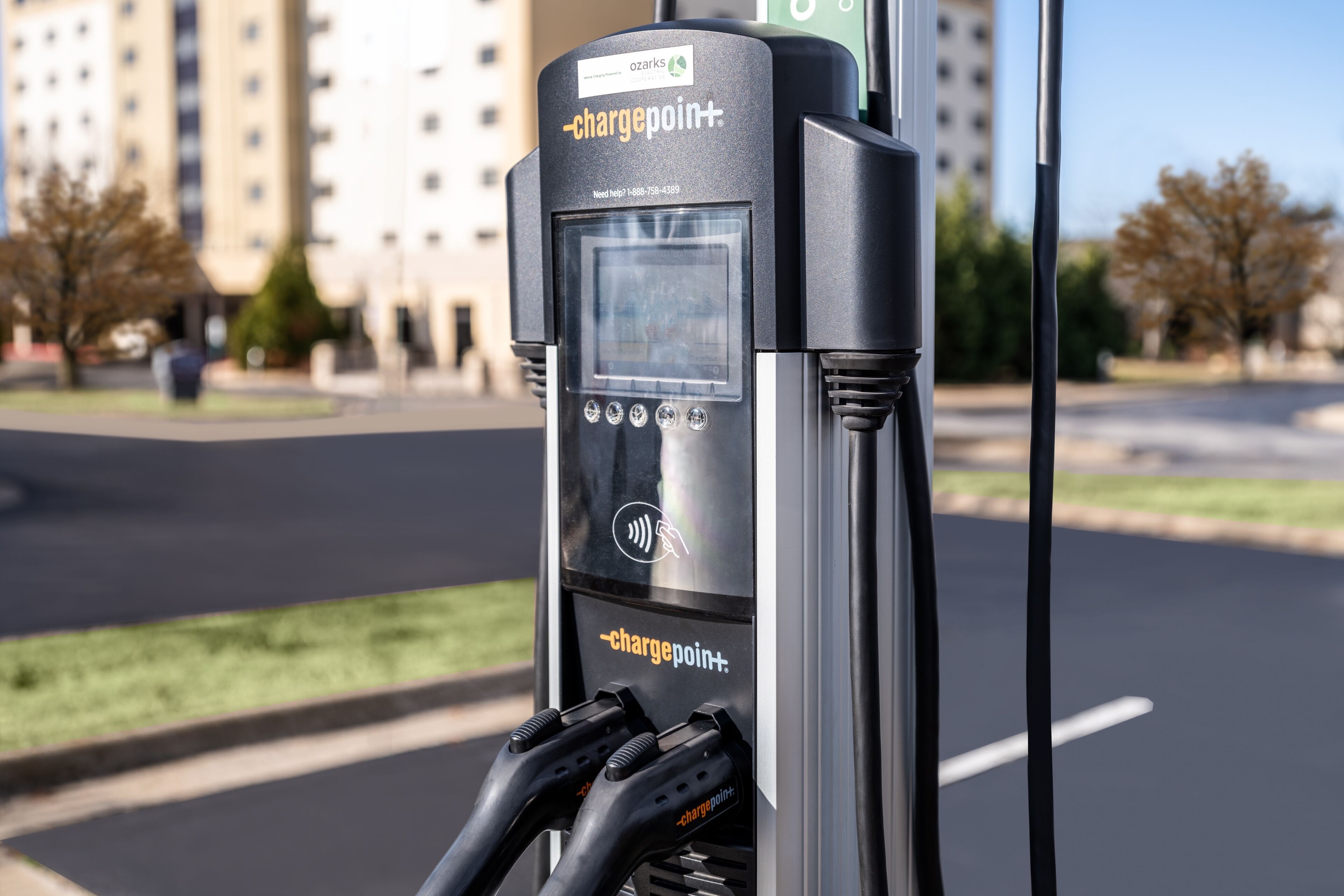 Uma estação de carregamento para veículos elétricos chargepoint+, com visor digital, cabos de carregamento e teclado.
