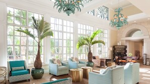 Uma sala de estar ampla com grandes janelas, assentos confortáveis e plantas decorativas.