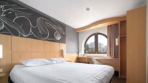 Quarto de hotel com uma cama grande, uma escrivaninha e um guarda-roupa.
