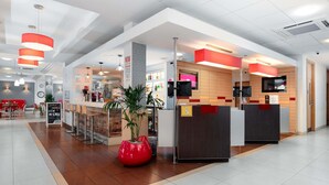 Um lobby moderno de hotel com balcão de recepção, área de estar e bar.