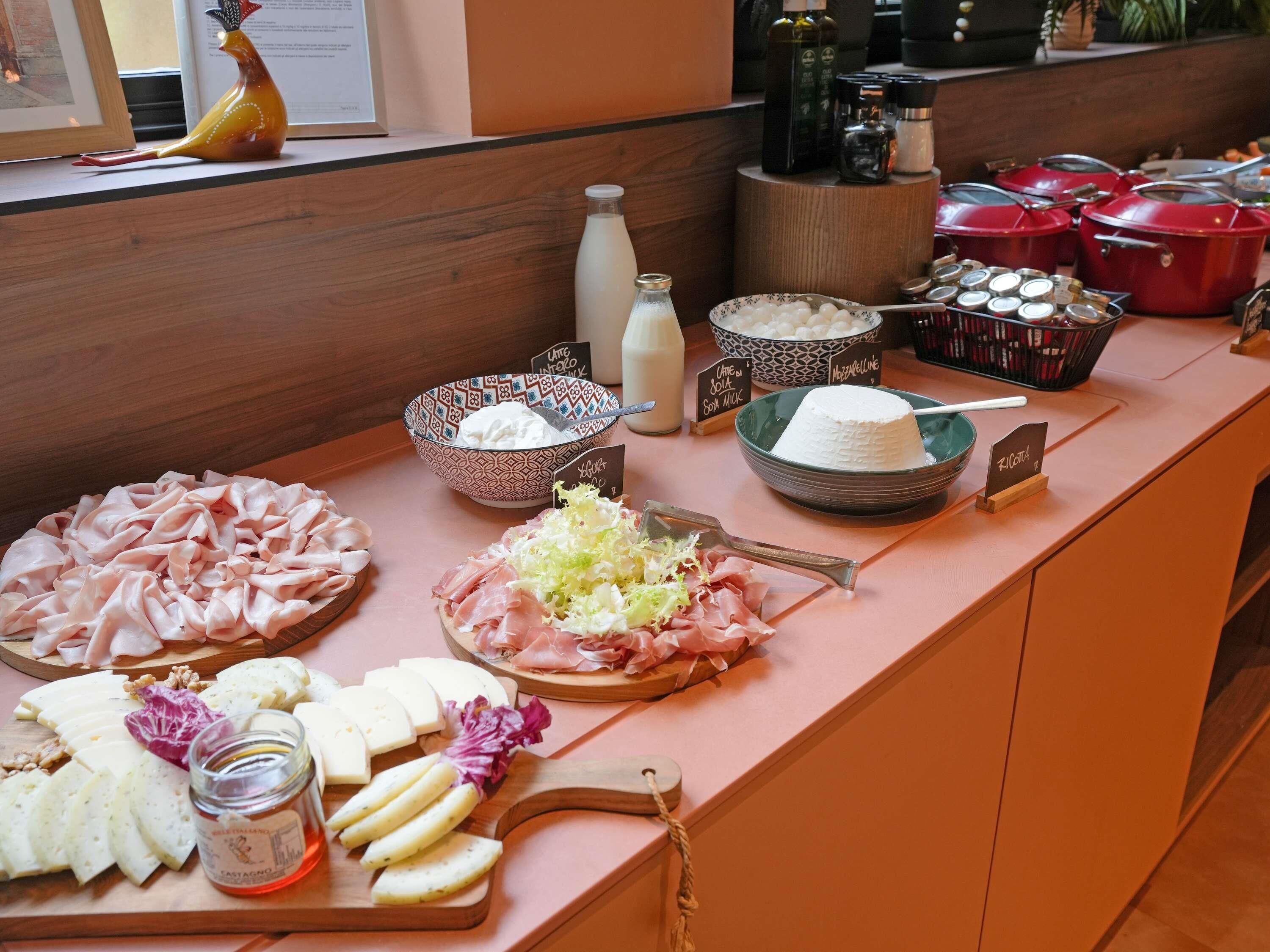 Buffet com diversos alimentos, incluindo carnes, queijos e acompanhamentos.