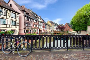 Fileira de casas tradicionais de enxaimel ao longo de um canal, com uma bicicleta estacionada sobre uma ponte.