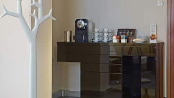 Uma moderna receção de hotel com uma máquina de café, um quadro de ementa e uma escultura decorativa de árvore.