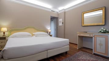 Quarto de hotel com uma cama grande, uma escrivaninha, um espelho e uma mesa de cabeceira com luminárias.