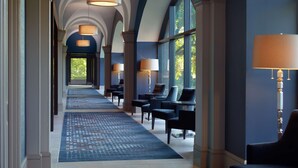 Um hall de hotel com um longo corredor, tetos em arco e áreas de estar com luminárias.