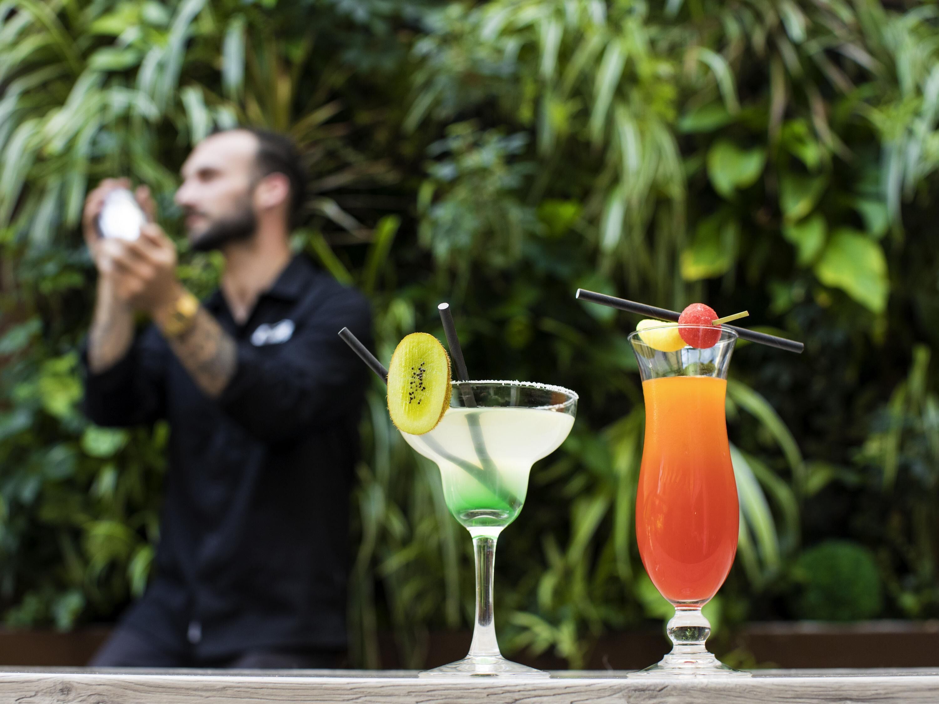 Dois cocktails numa mesa, com uma pessoa ao fundo.