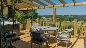 Um deck de madeira com pérgola, área de estar externa e vista para o campo.