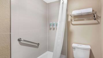 Um banheiro com chuveiro, vaso sanitário, porta-toalhas e dispensador de álcool em gel.