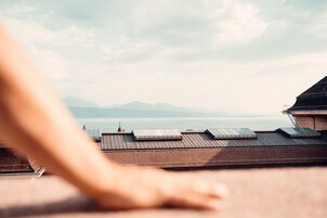Terraço com painéis solares e vista para o mar e montanhas.