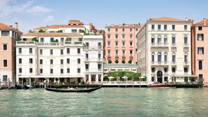 Uma fileira de edifícios históricos com sacadas, um canal e gôndolas.