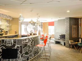 Uma área de bar moderna com balcão, banquetas e iluminação pendente.