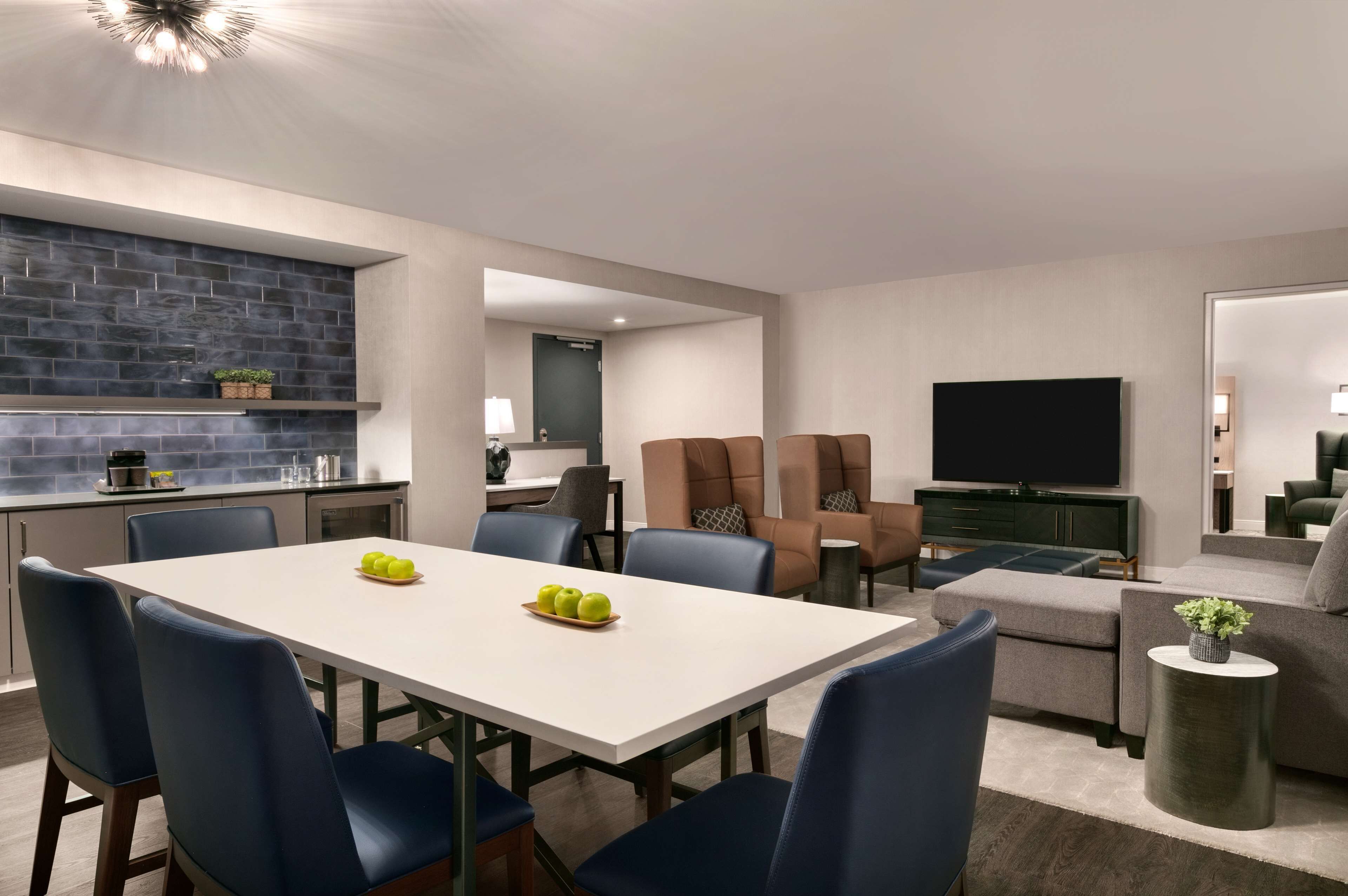 Uma sala de estar moderna com área de jantar, cozinha e televisão.