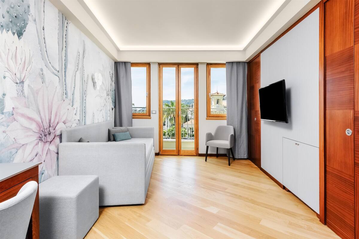 Uma sala de estar moderna com um sofá cinzento, uma mesinha e uma TV fixada na parede.
