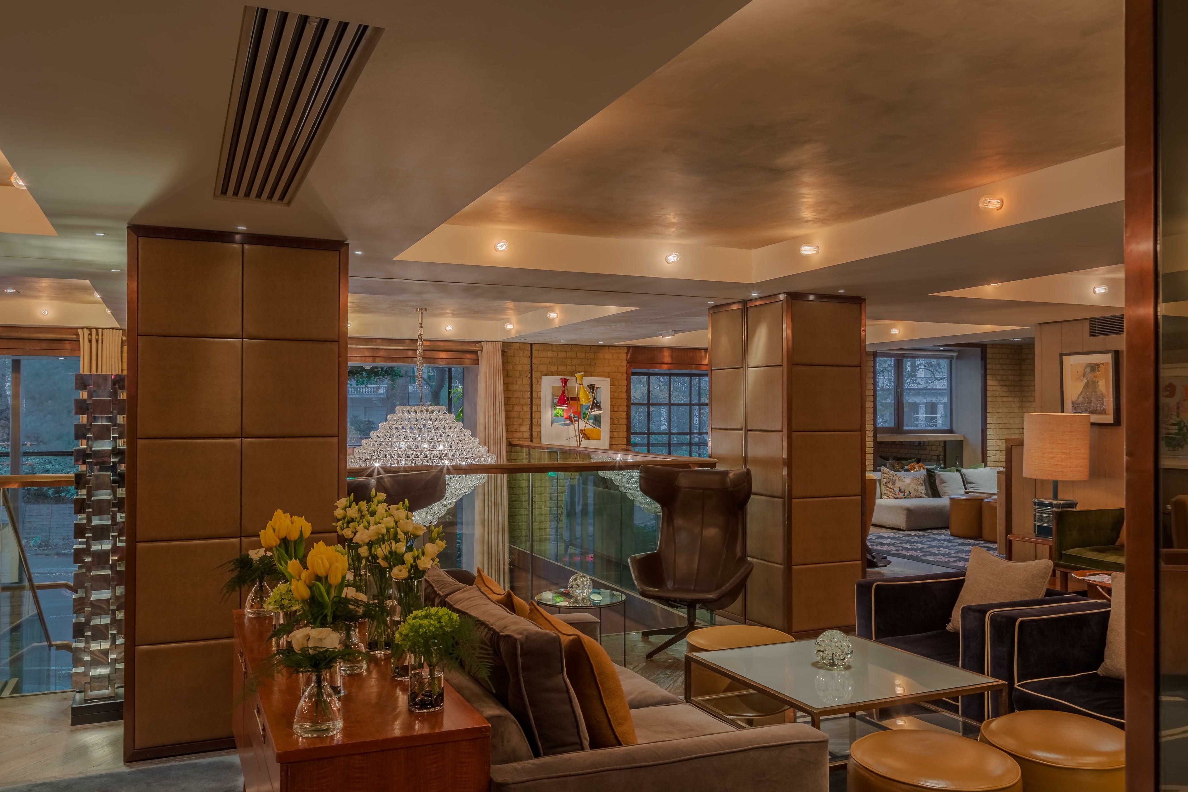 Um interior moderno com área de estar, mesa de vidro e lustre decorativo.