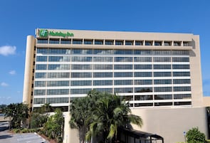 Um edifício de hotel com vários andares, fachada plana e um logotipo verde no topo.