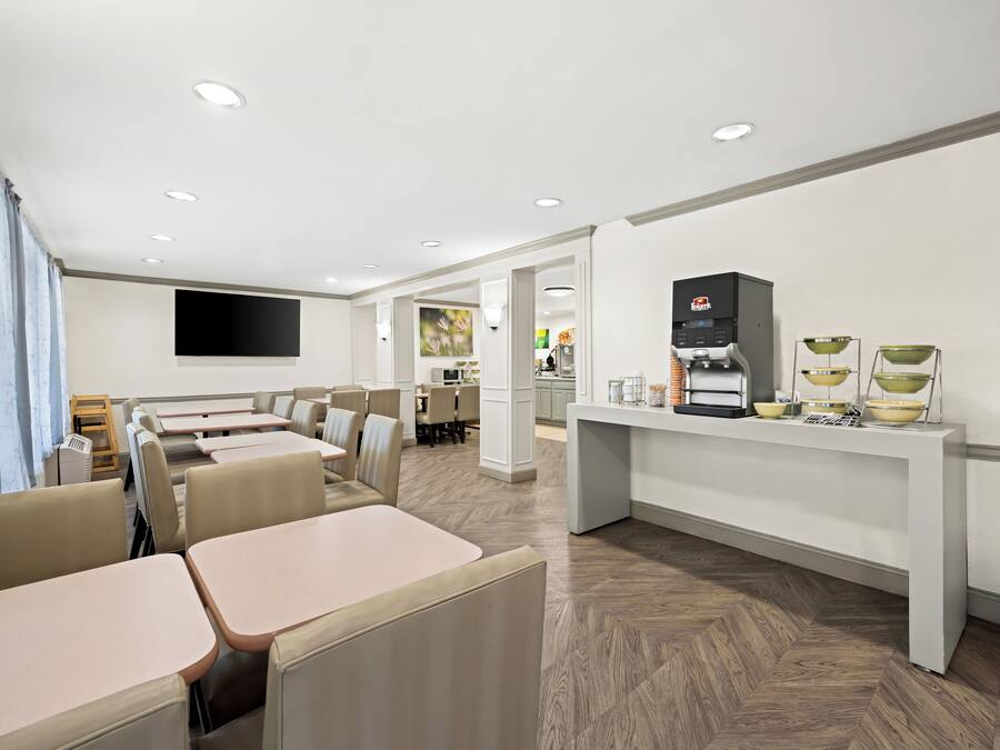 Um saguão de hotel moderno com áreas de estar, um espaço para café e uma televisão de tela plana na parede.
