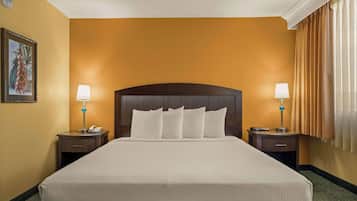 Quarto de hotel com uma cama grande, duas mesas de cabeceira com abajures e uma obra de arte na parede.
