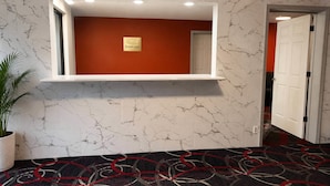Uma área de recepção com parede de mármore, balcão de recepção e um letreiro com a inscrição 'Econolodge'.