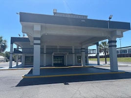 Um posto de gasolina com toldo, várias bombas de combustível e uma câmera de segurança.