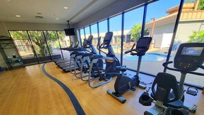 Uma academia com máquinas de cardio, um remo e um banco de musculação.