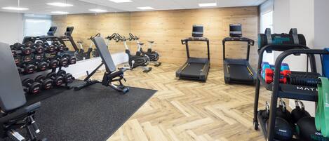 Uma academia com diversos equipamentos de exercícios, incluindo halteres, esteiras e bicicletas ergométricas.
