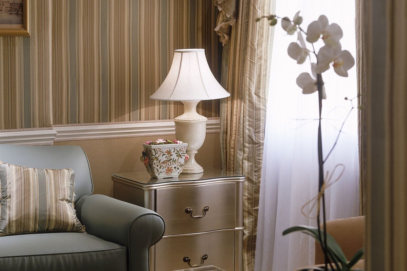 Quarto com sofá, luminária, um objeto decorativo e uma planta.