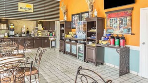 Uma área de café da manhã com uma placa Daybreak, um balcão com máquinas de café e um mural de um café na parede.