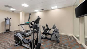 Sala de ginástica com esteiras, elípticos e bicicleta ergométrica.