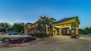 Hotel com posto de gasolina, um carro estacionado na frente e uma placa de 'Não Estacionar'.