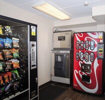 Máquina de vendas automática com lanches e máquina de Coca-Cola com cubos de gelo.