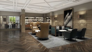 Um hall espaçoso com design moderno, destacando um piso de madeira em padrão herringbone, uma ampla área de estar com sofás e poltronas, uma mesa de centro e uma estante com objetos decorativos.