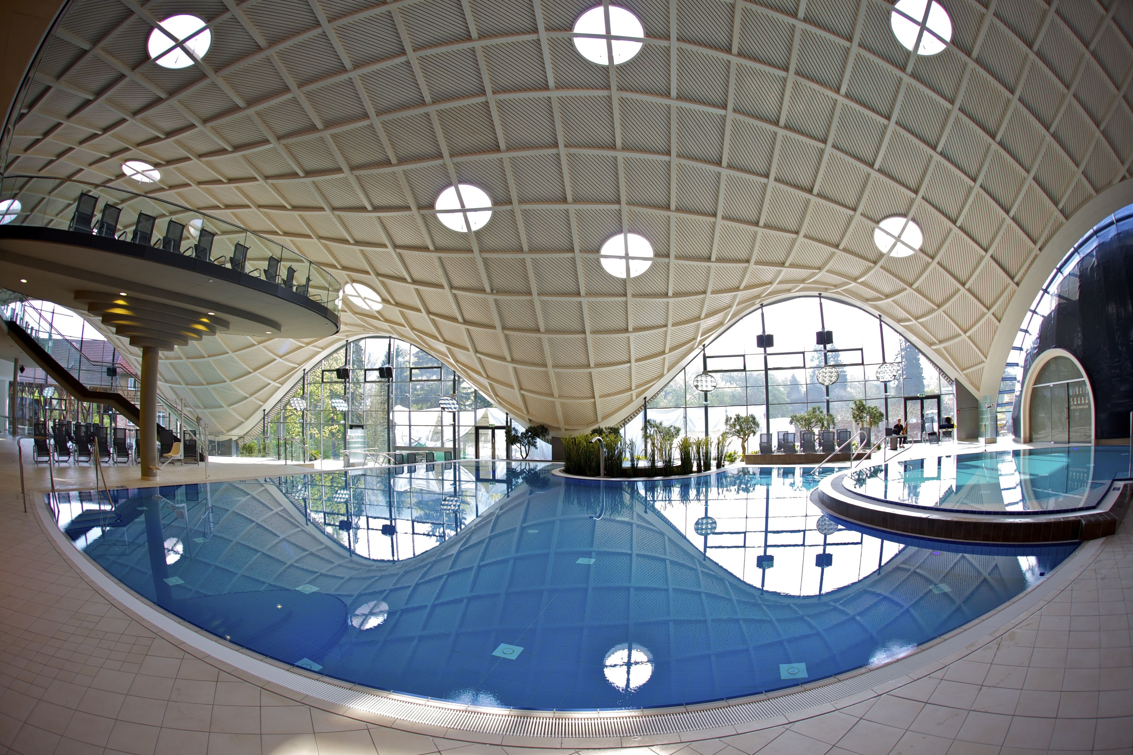 Piscina interna com teto alto e abobadado e grandes janelas.