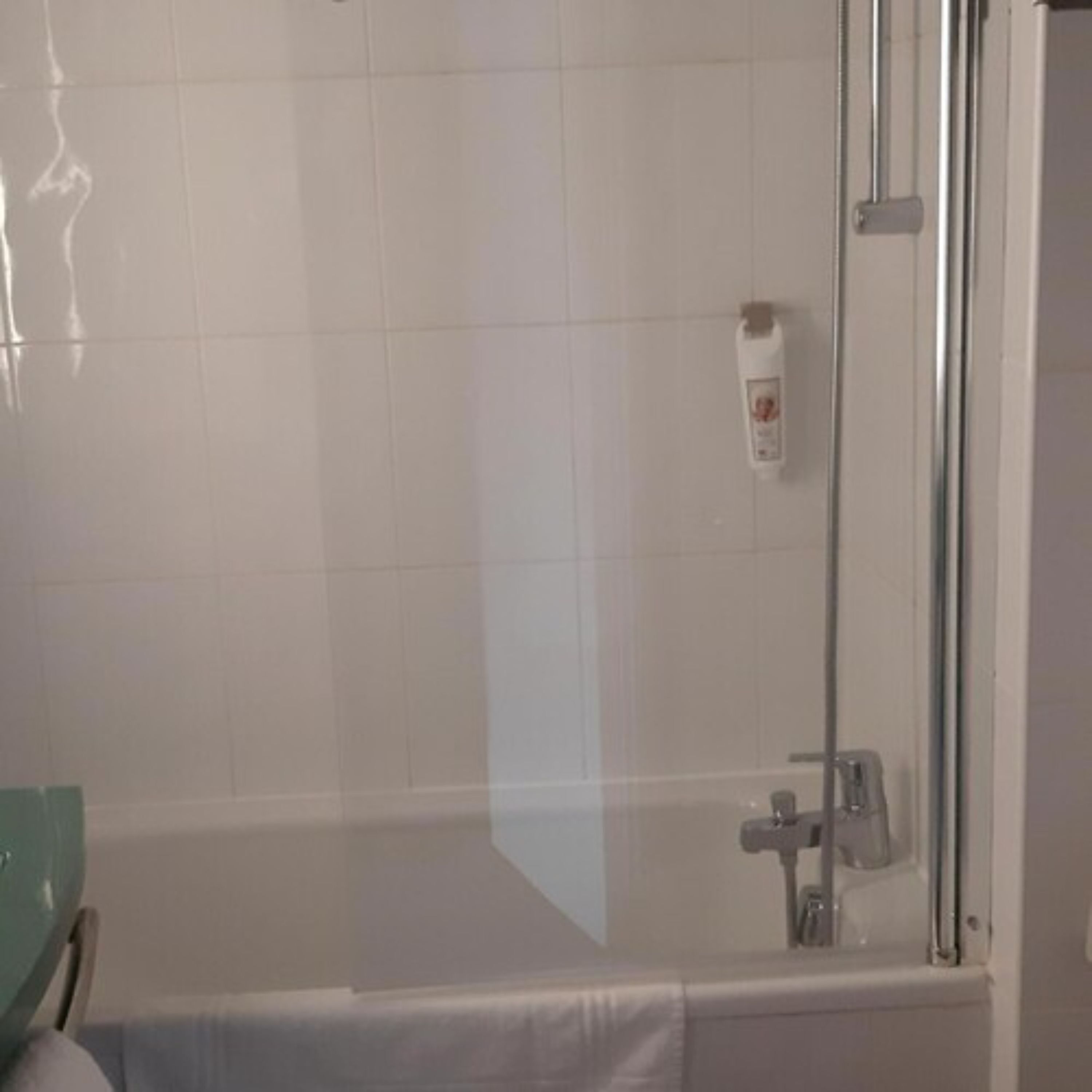 Um banheiro com box de vidro, banheira branca e porta-toalhas.