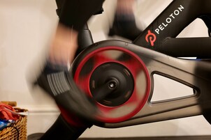 Uma bicicleta ergométrica com o logotipo Peloton e uma cesta com objetos.