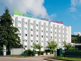 Um hotel de vários andares com design moderno, apresentando uma placa grande com a inscrição 'ibis Styles Hotel Courtepaille' no topo.