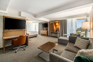 Quarto de hotel moderno com televisão de tela plana, escrivaninha, sofá confortável e cama.
