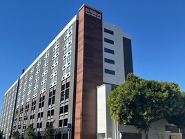 Um hotel Hilton Garden Inn com fachada moderna, vários andares e uma placa bem visível.