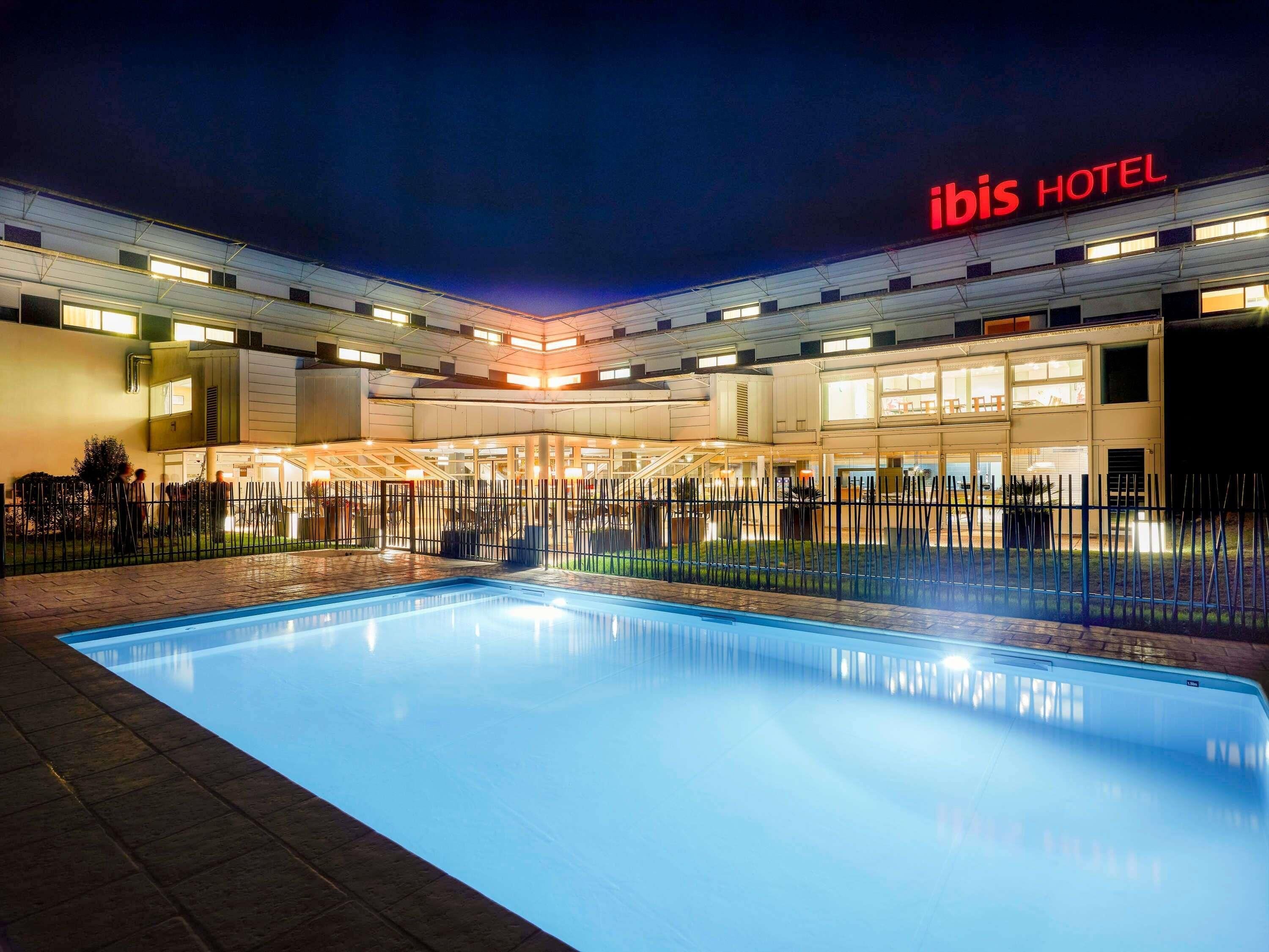 Um hotel Ibis com piscina e pátio cercado.