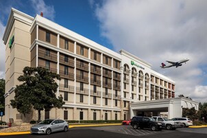 Hotel com fachada moderna, várias sacadas e estacionamento com diversos carros.