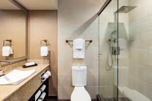Casa de banho moderna com lavatório, sanita e cabine de duche com vidro.