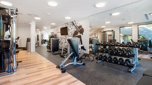 Uma academia moderna com diversos equipamentos de exercício, incluindo esteiras e halteres, e um grande espelho na parede.