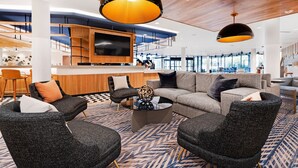 Uma área de estar moderna com sofás, mesa de centro e luminárias pendentes.