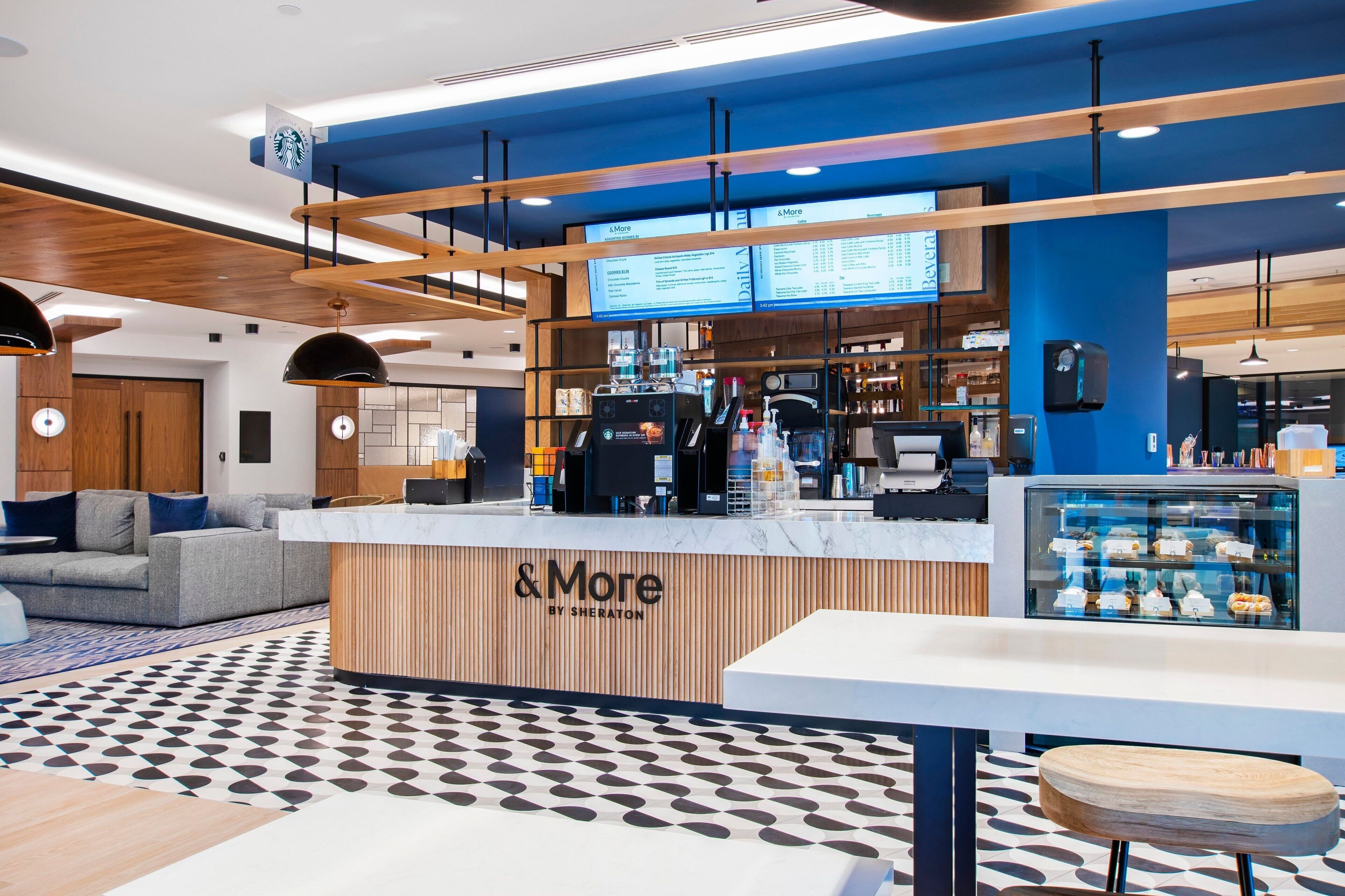 Um hall de hotel moderno com um balcão de café, área de estar e piso estampado.