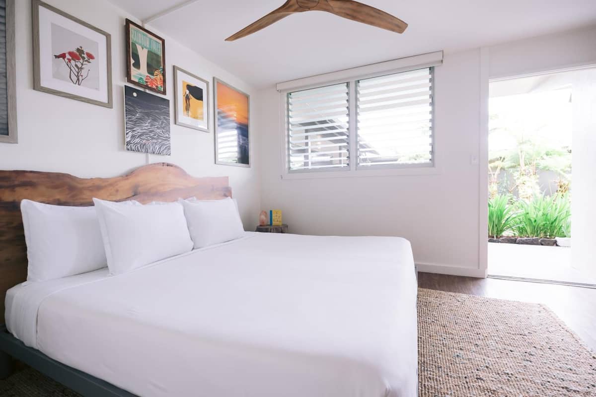 Quarto com uma cama grande, cabeceira de madeira e janela com persianas.