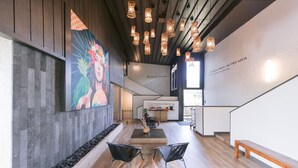 Um interior moderno com piso de madeira, cadeiras de balanço pretas, uma escada e um mural na parede.