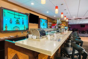 Uma área de buffet com um balcão extenso, várias cadeiras e uma vitrine com diversos itens.