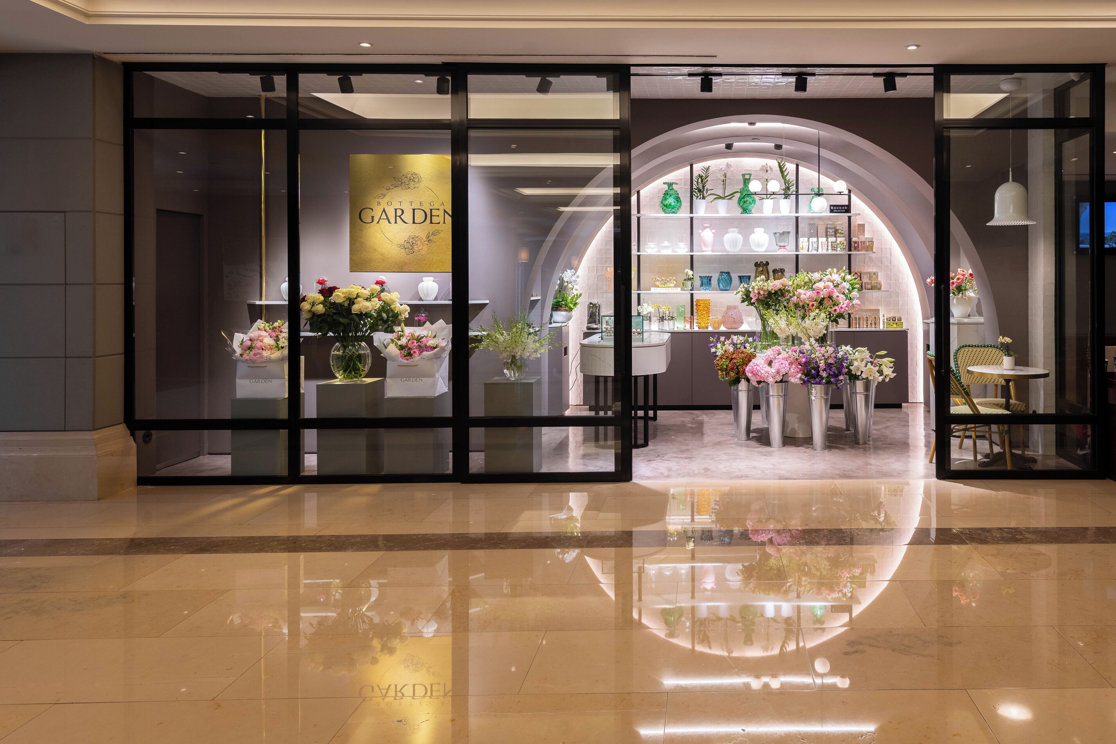 Vitrine com entrada de vidro, exibindo arranjos florais e diversos artigos nas prateleiras.