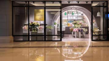 Vitrine com entrada de vidro, exibindo arranjos florais e diversos artigos nas prateleiras.