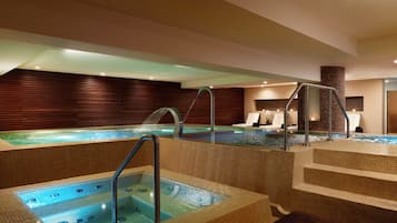 Uma área de spa com hidromassagem, um jacuzzi menor e uma área de estar com cadeiras de apoio.